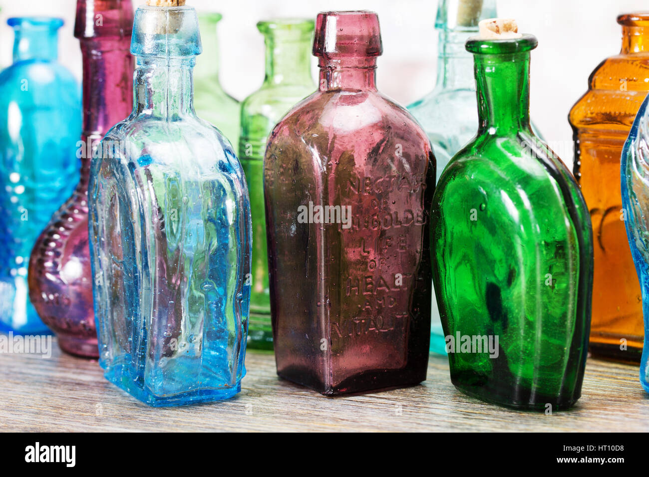 Selection of coloured glass bottles on a rustic background Stock Photo ...