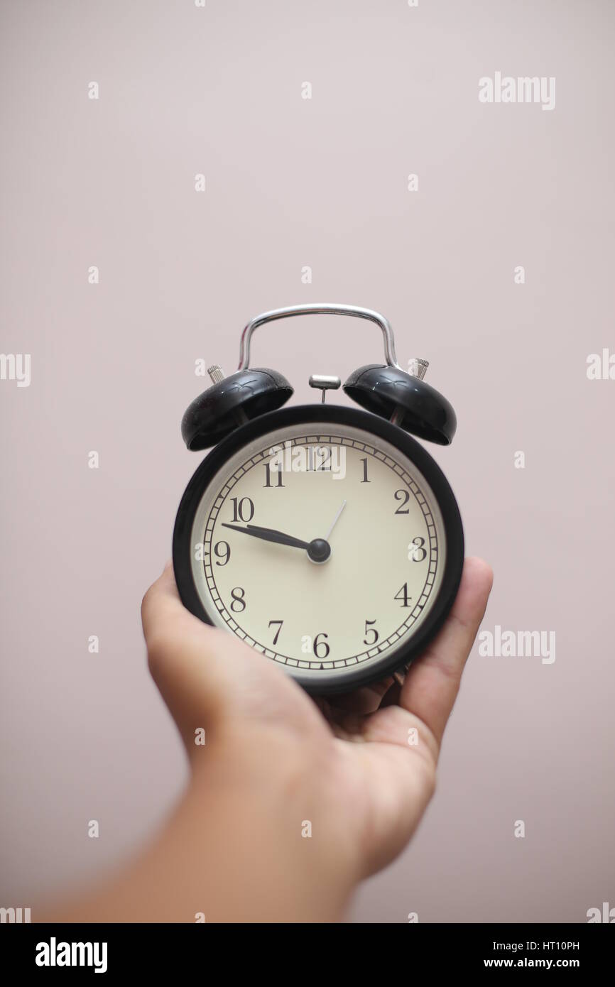 Hand holding retro alarm clock isolated on purple background Stock ...