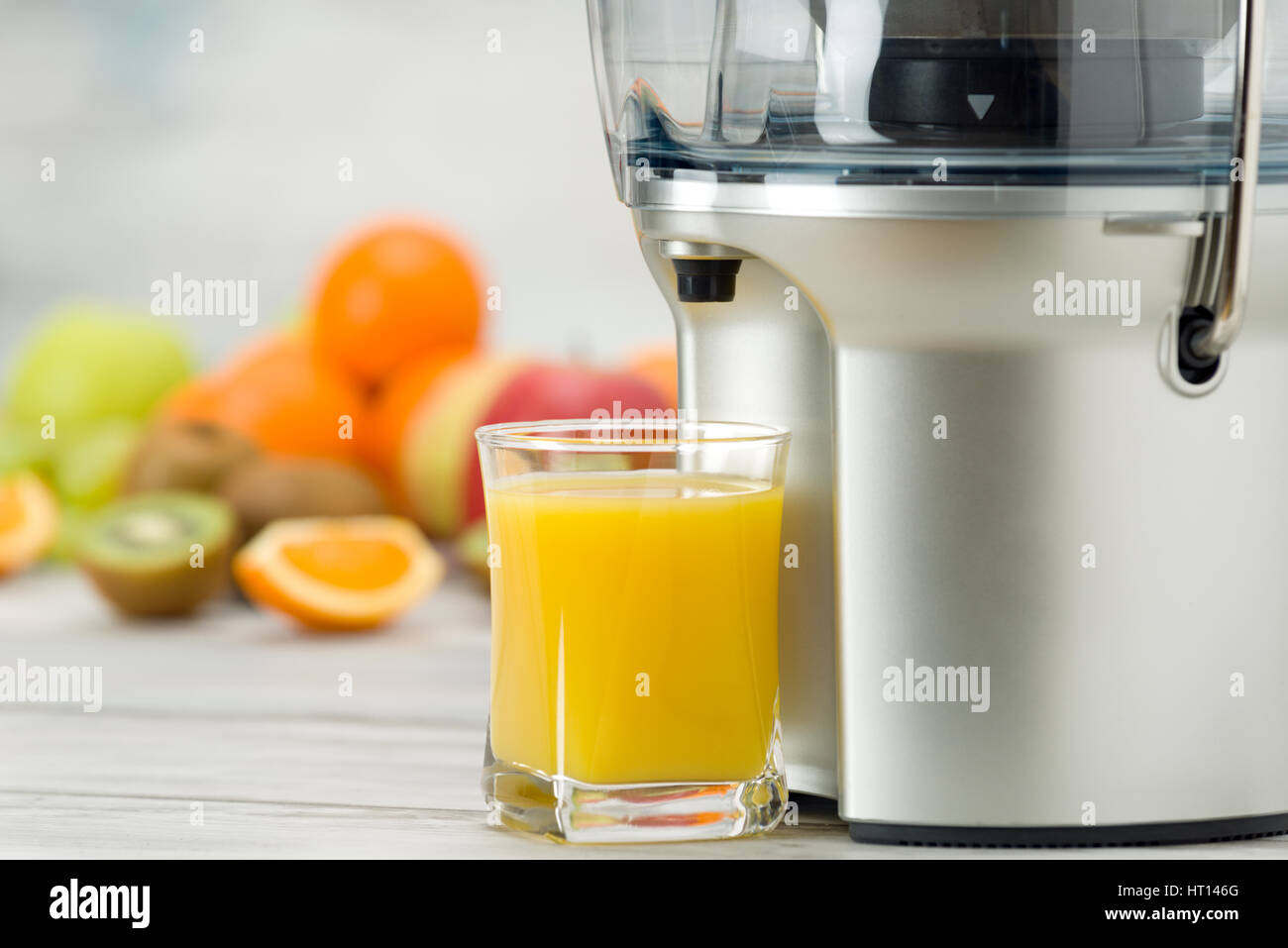 Modern electric juicer, various fruit and glass of freshly made juice ...
