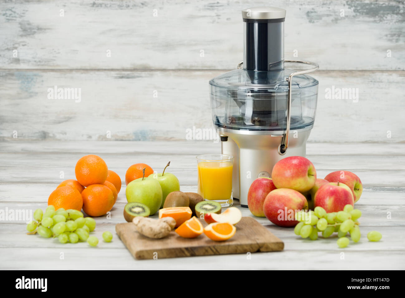 Modern electric juicer, various fruit and glass of freshly made juice ...