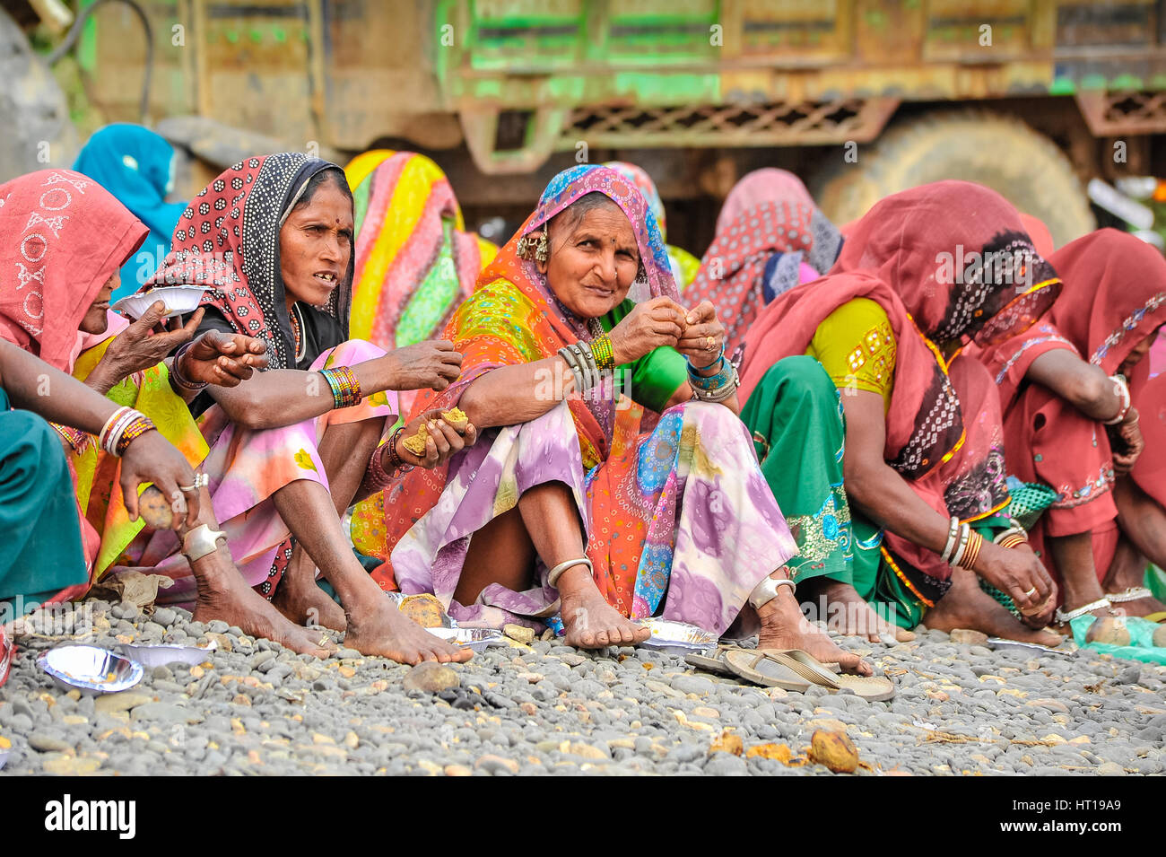 Rajasthani women in colourful saris sit eating Stock Photo - Alamy