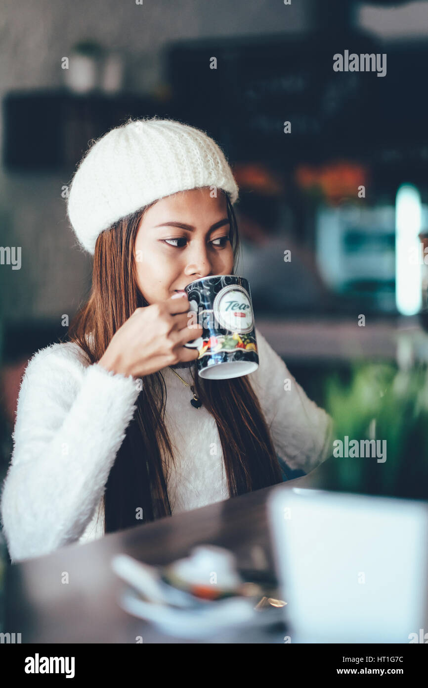 Beautiful girl in white outfit drinking tea in club Stock Photo - Alamy