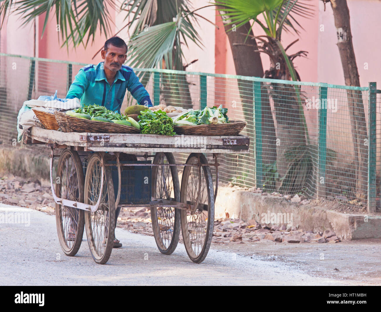 An unidentified trader wheeling his cart laden with vegetables to a ...