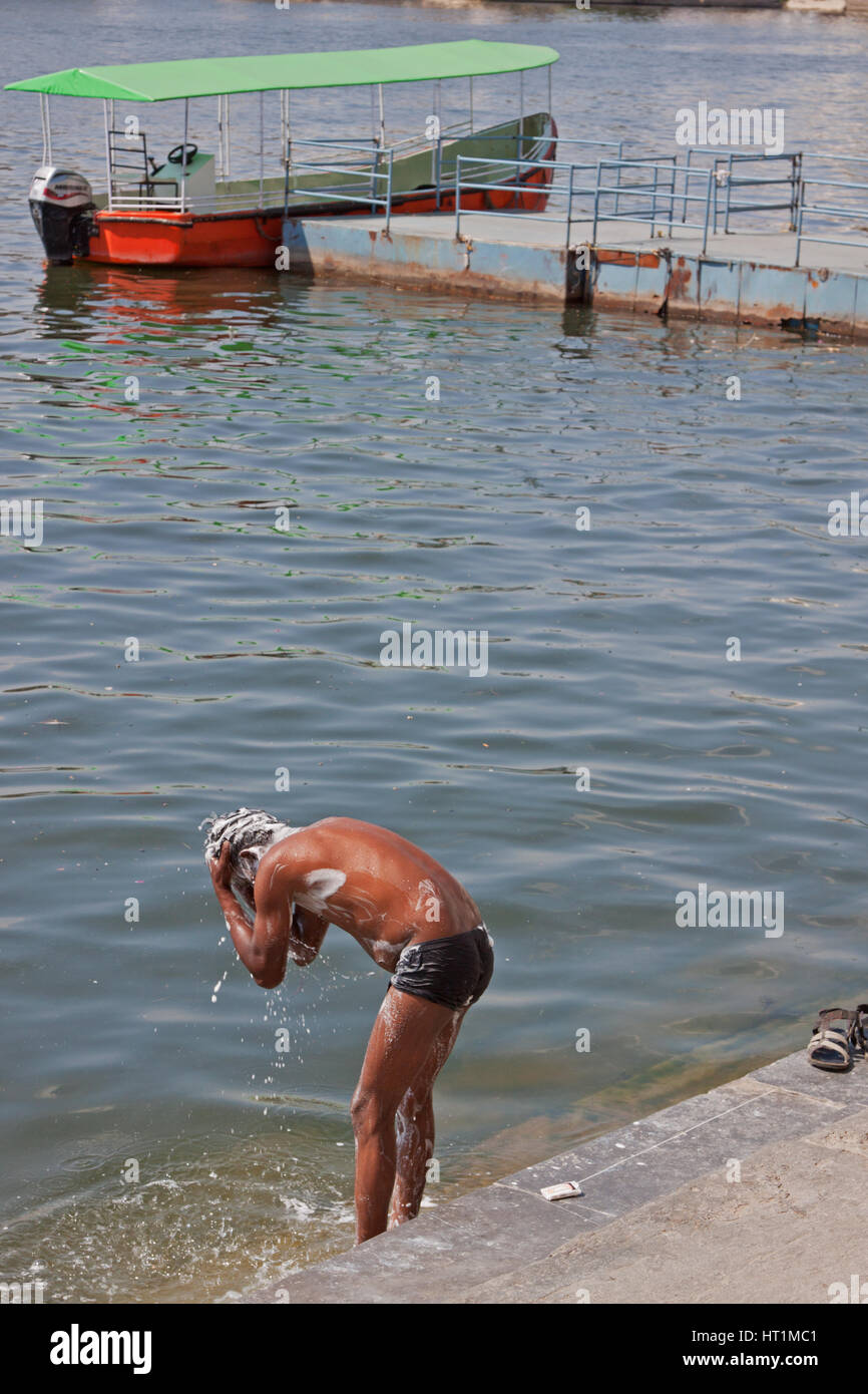 Unidentified youth bathing at a ghat, a series of steps leading down to ...