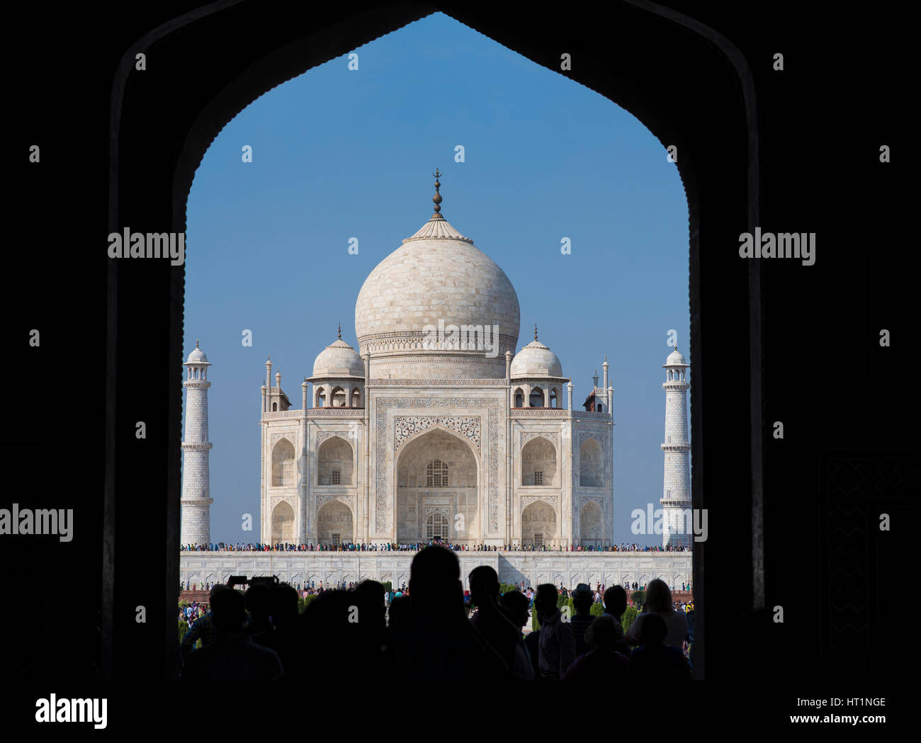 Taj Mahal viewed through entrance gate and silhouette of people going ...