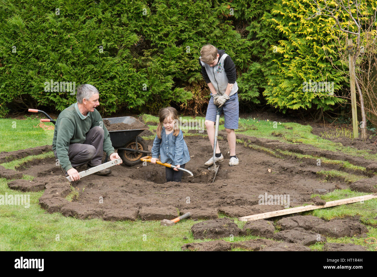 grandfather father with children digging wildlife pond in garden Stock ...