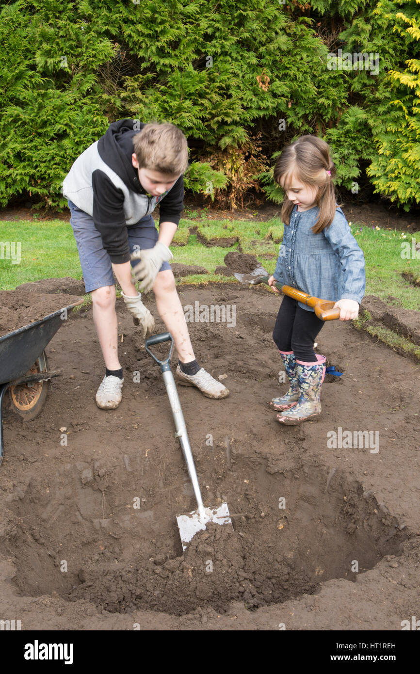 young girl and boy digging wildlife pond in garden Stock Photo - Alamy