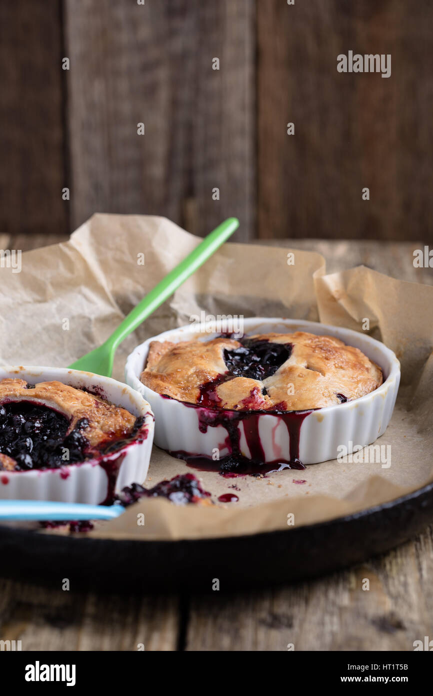 Rustic homemade blueberry mini pie in small ceramic bowls on wooden ...