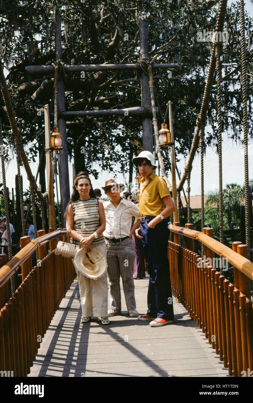 Three siblings stand on a rope bridge at Disney World amusement park ...