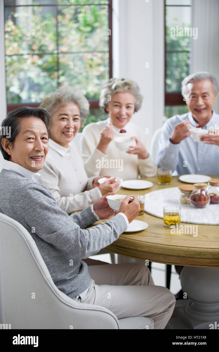 Happy senior friends eating together Stock Photo - Alamy