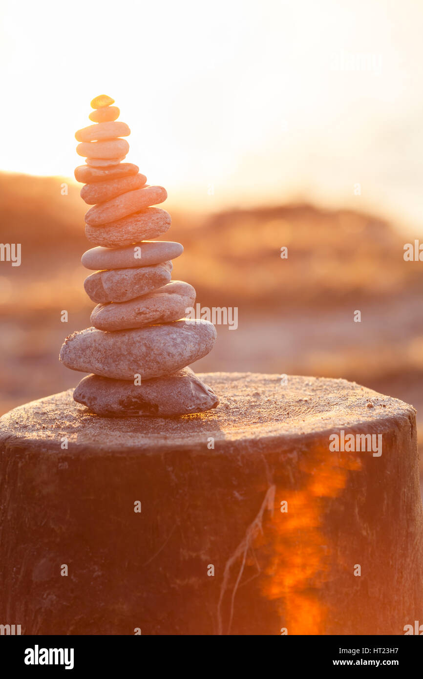 Tower of pebbles with shell on top at bright evening sunshine, built on ...