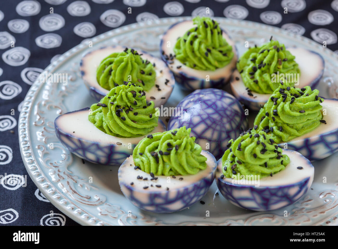 Deviled egg with avocado with spider web pattern topped black sesame ...