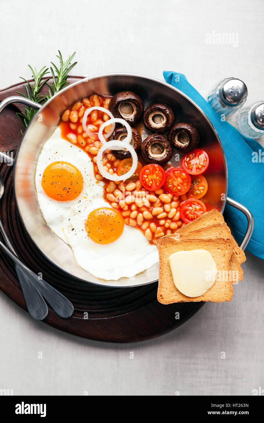 Full English Breakfast with fried eggs, beans, toasts, tomatoes ...