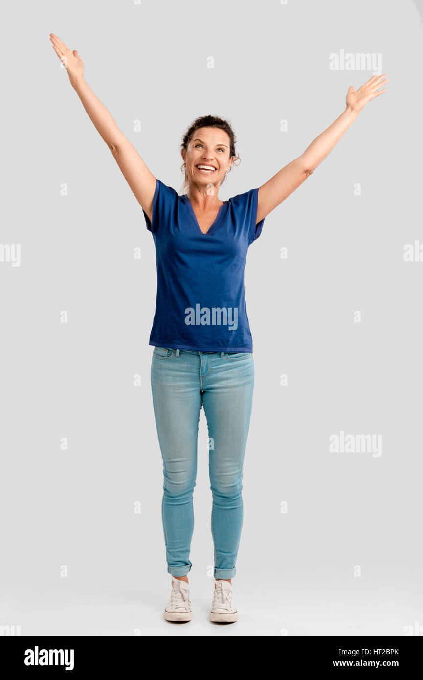 Portrait of a happy middle aged brunette with arms up Stock Photo - Alamy