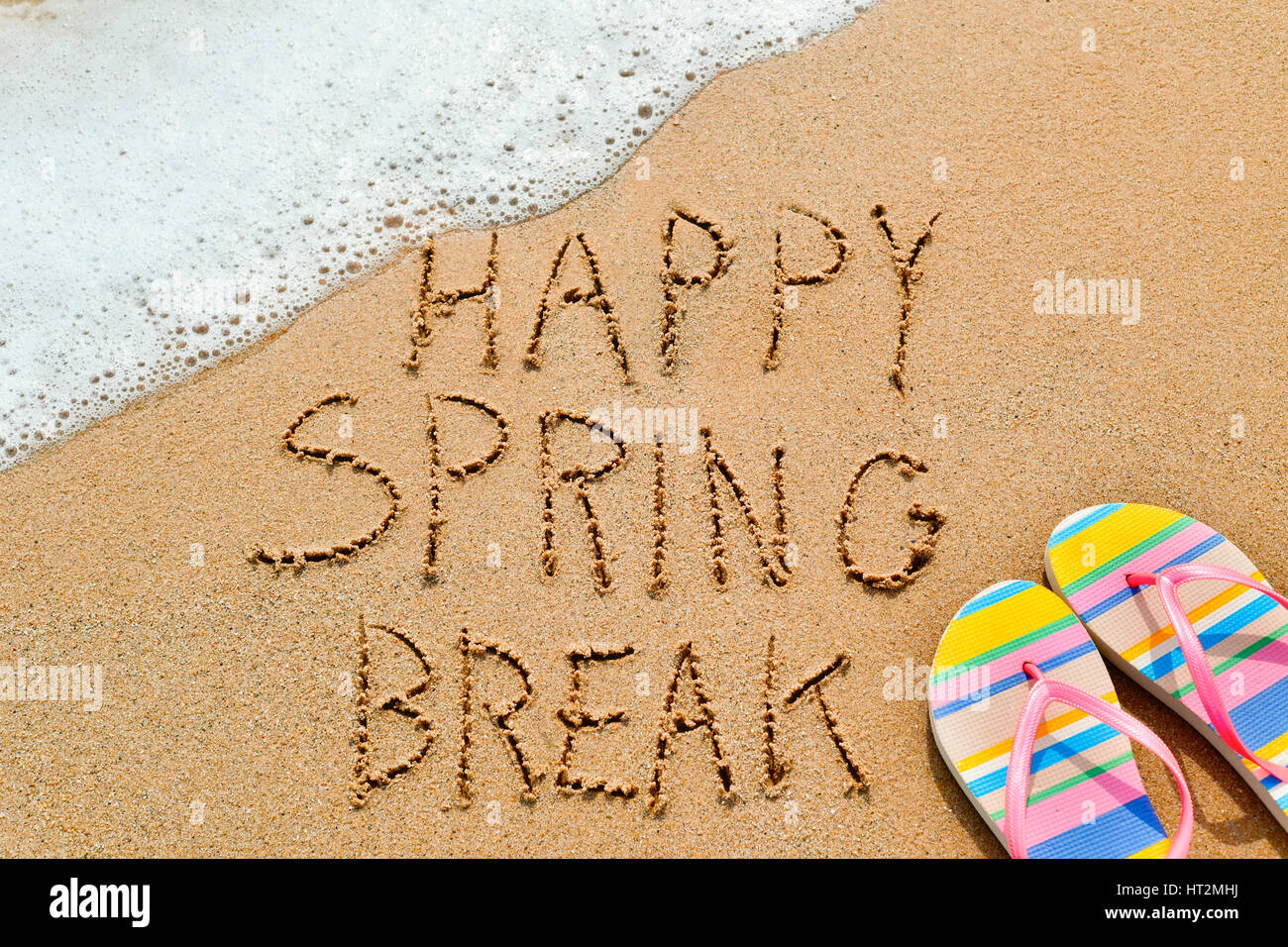 closeup of the text happy spring break written in the sand of a beach ...
