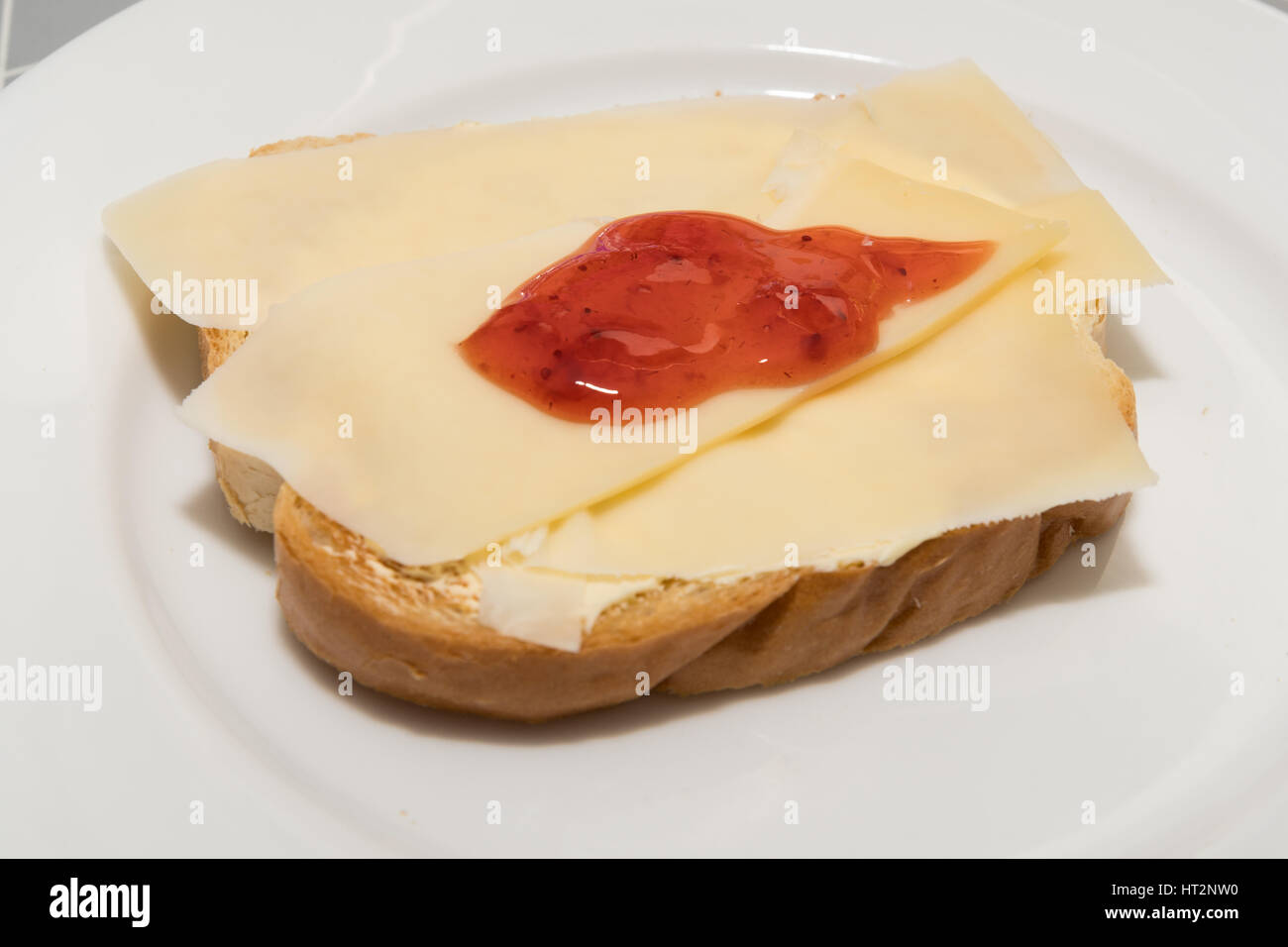 One toast topped with cheese and jam on a white plate Stock Photo - Alamy
