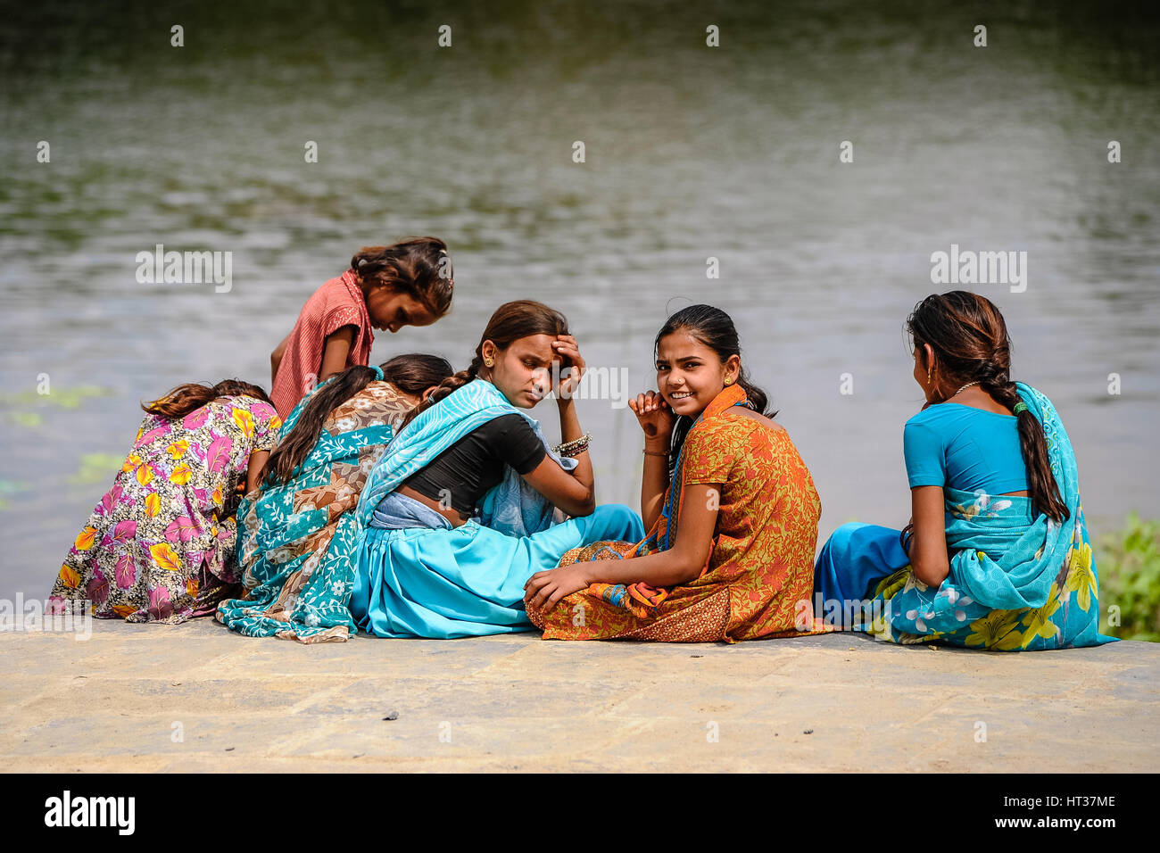 Indian girls sat on a step by a river Stock Photo - Alamy