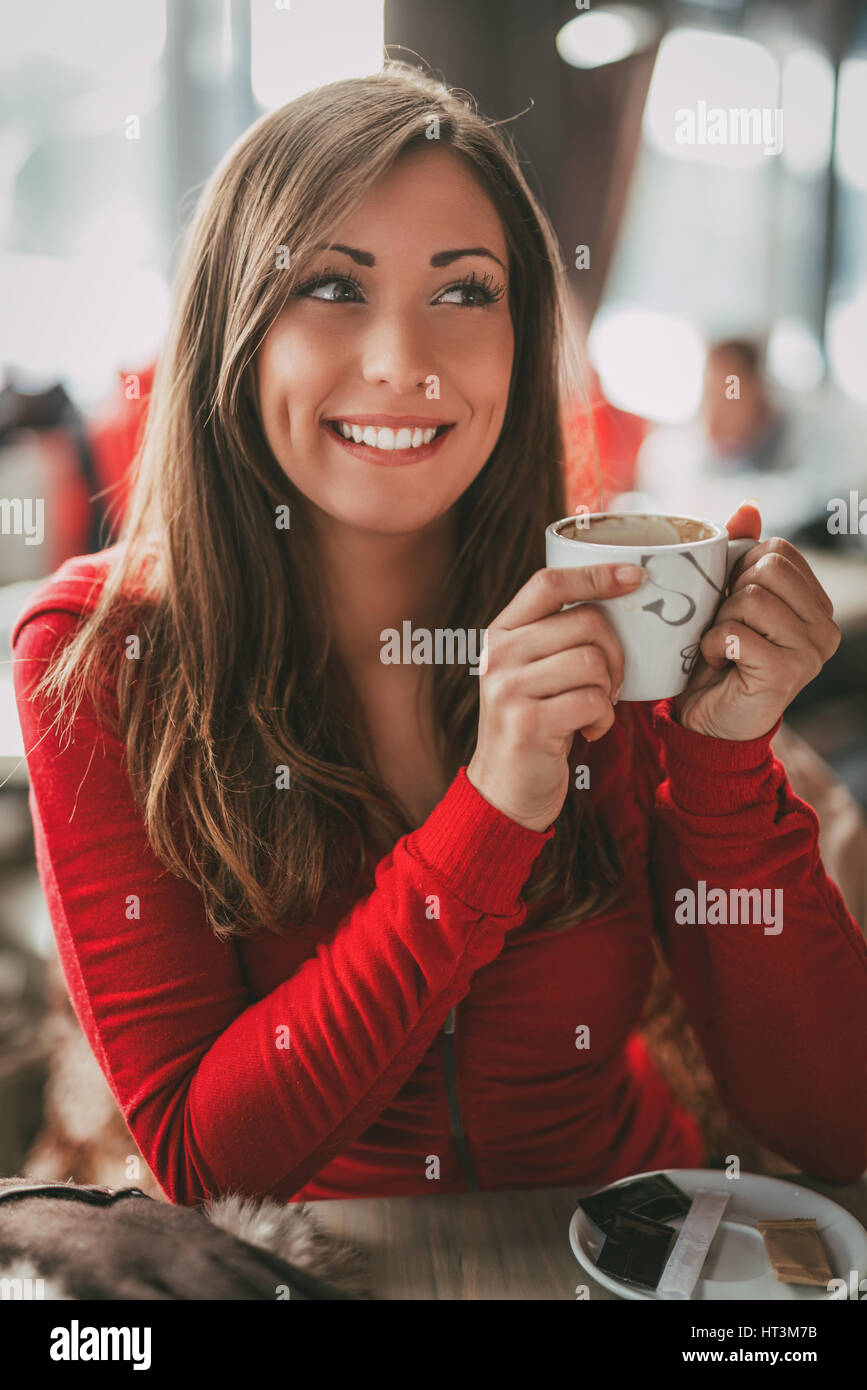Beautiful young smiling woman relaxing and enjoying a cup of coffee at ...