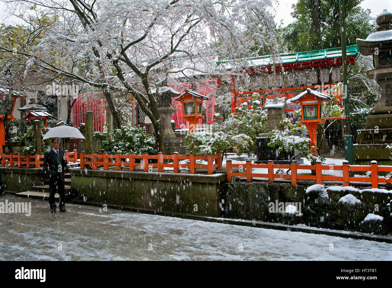 Japanese man with white umbrella in snowstorm at Yasaka Shinto shrine ...