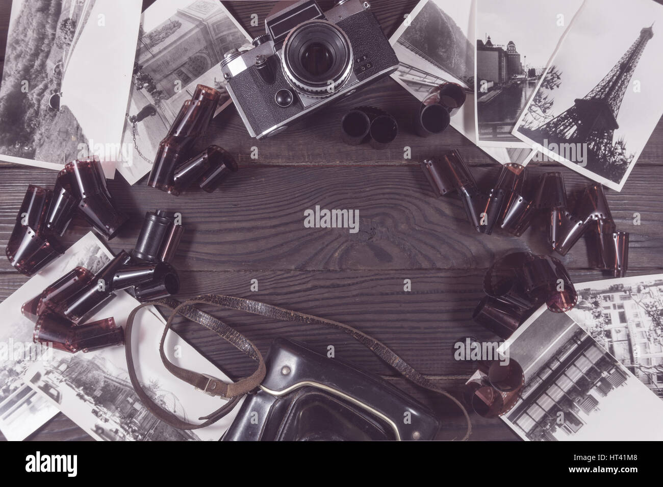 Old camera, film and black and white photographs are on the dark wooden ...