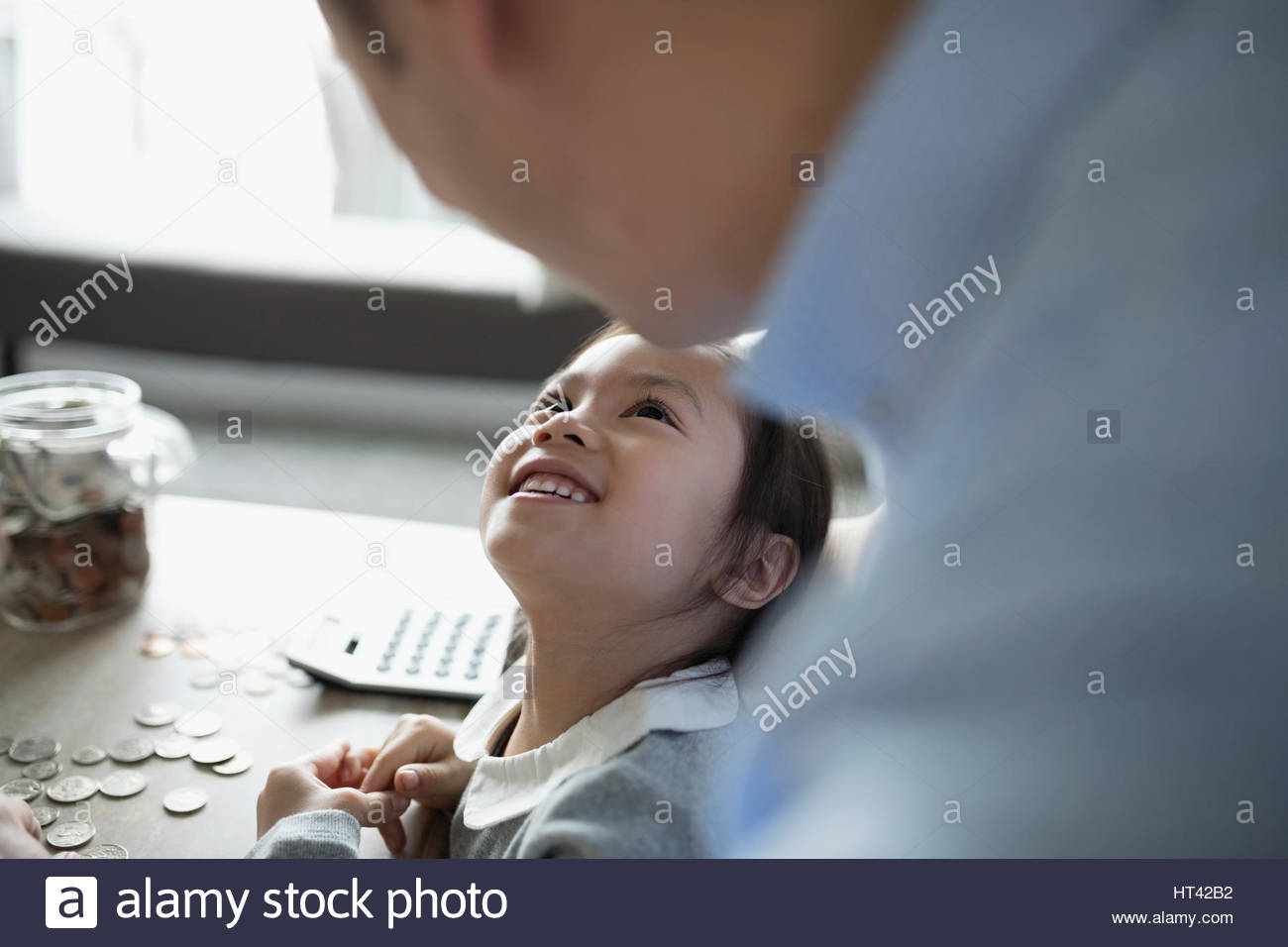 Smiling father counting allowance money, looking up and smiling at ...