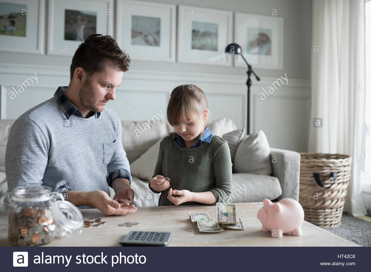 Father teaching daughter counting allowance money in living room Stock ...