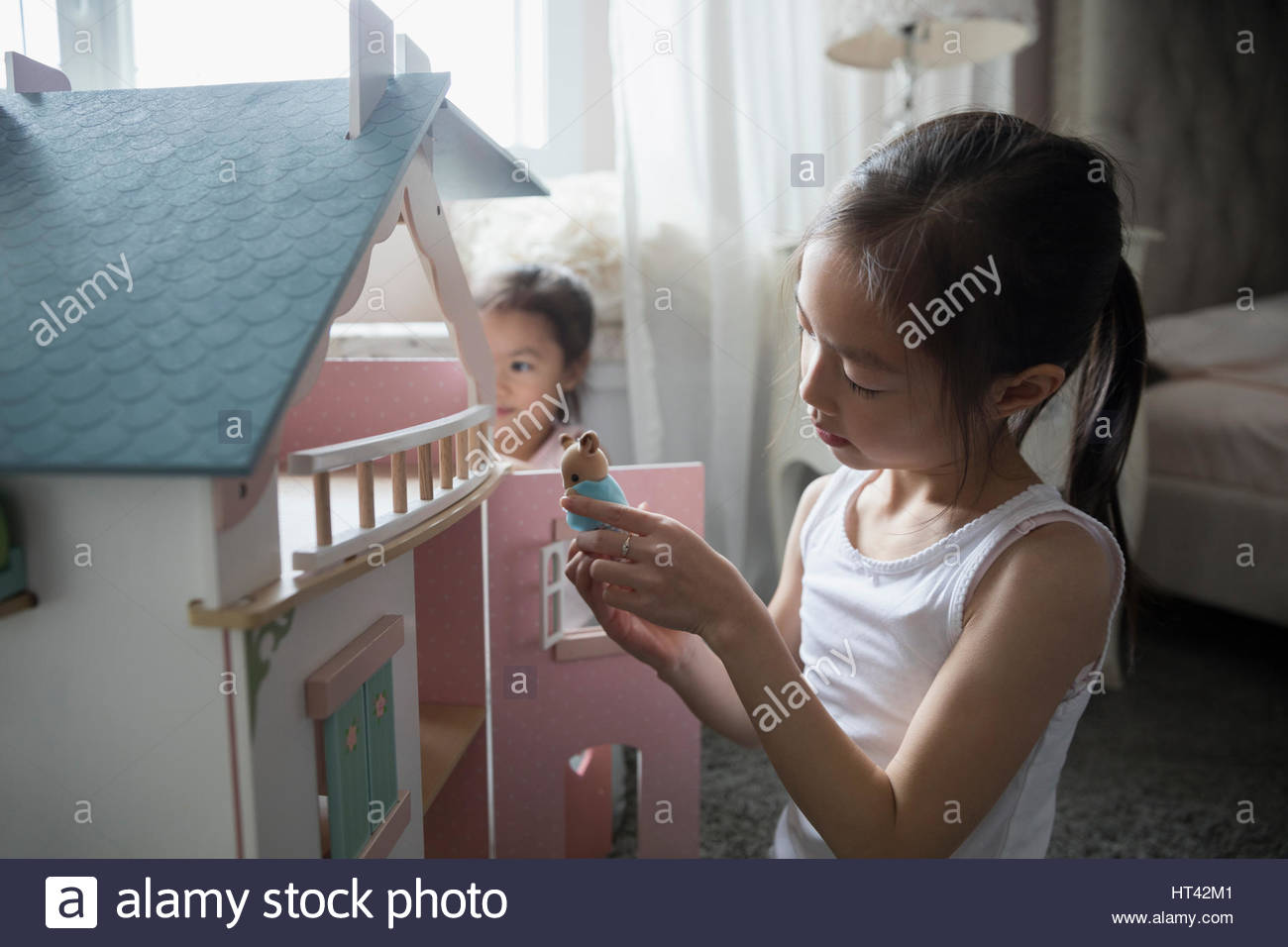 Sisters playing with dolls and dollhouse in bedroom Stock Photo - Alamy