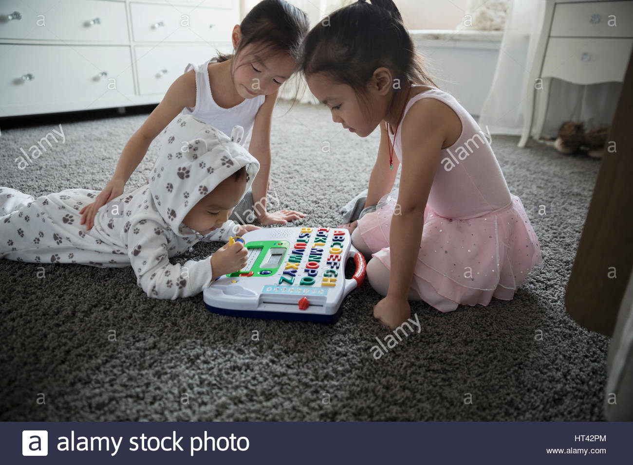 Sisters and brother playing alphabet game on carpet in bedroom Stock ...
