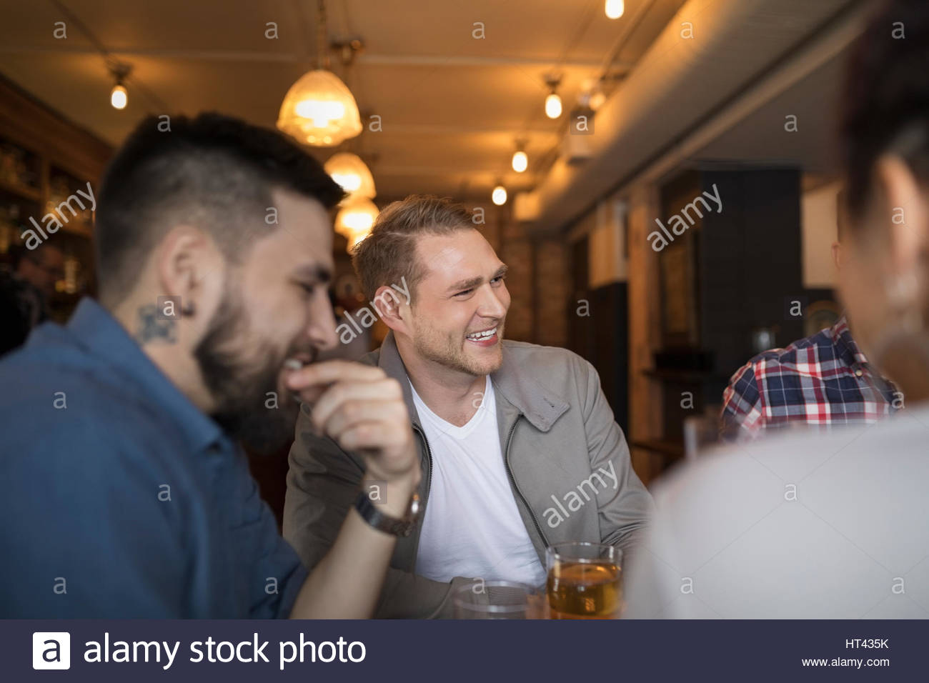 Man laughing with friends and drinking beer in bar Stock Photo - Alamy