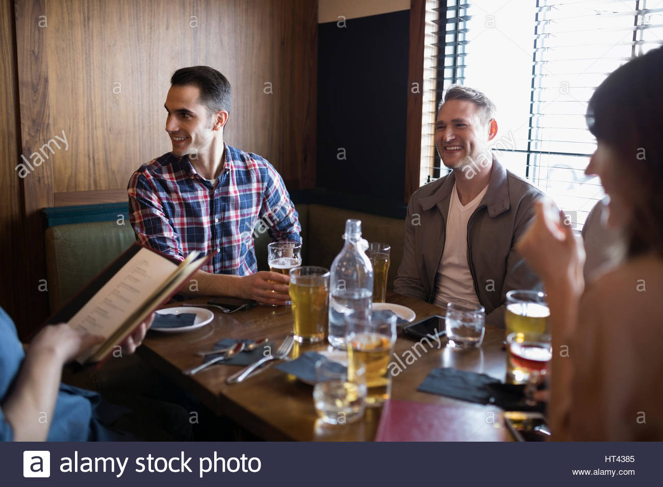 Friends drinking beer at table in bar Stock Photo - Alamy