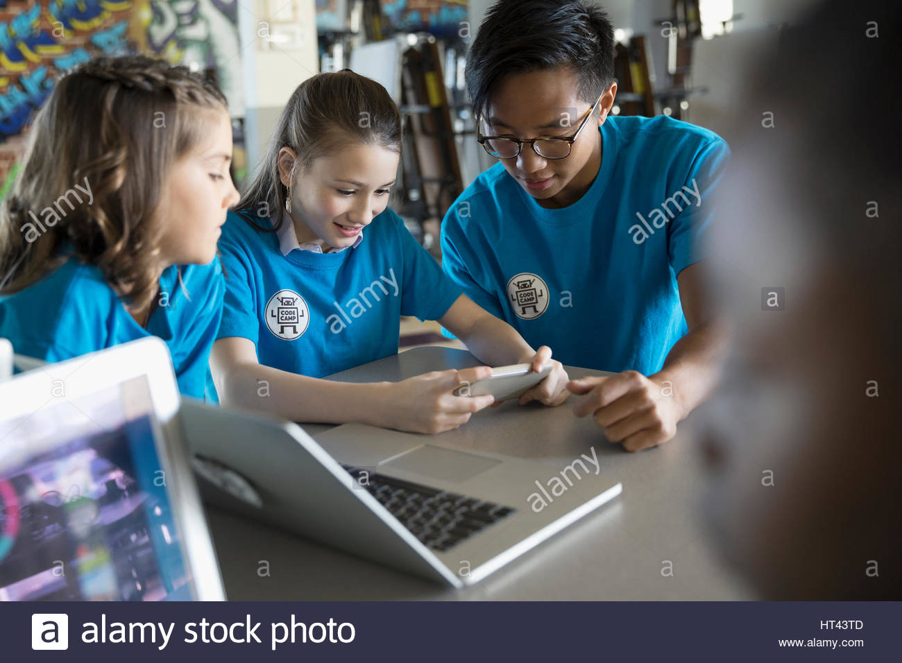 Male teacher and pre-adolescent girls using cell phone in classroom ...
