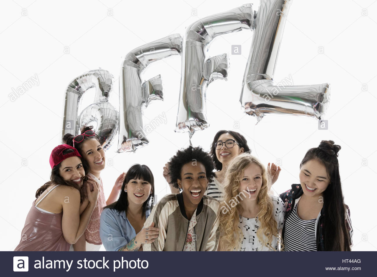 Portrait playful young women friends holding BFFL balloons against ...