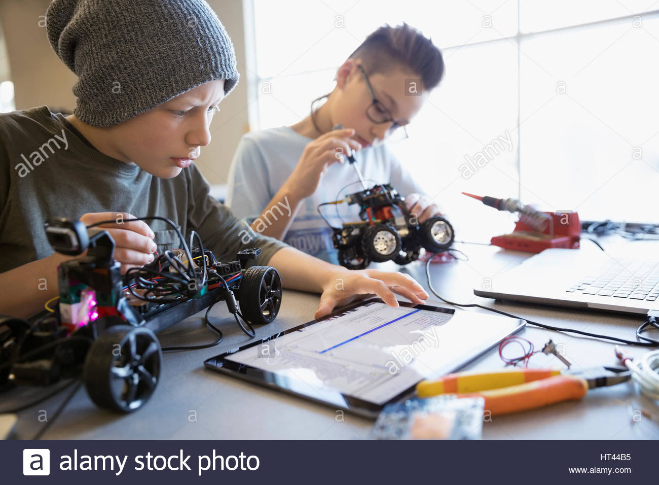 Pre-adolescent boys assembling and programming robotics at digital ...