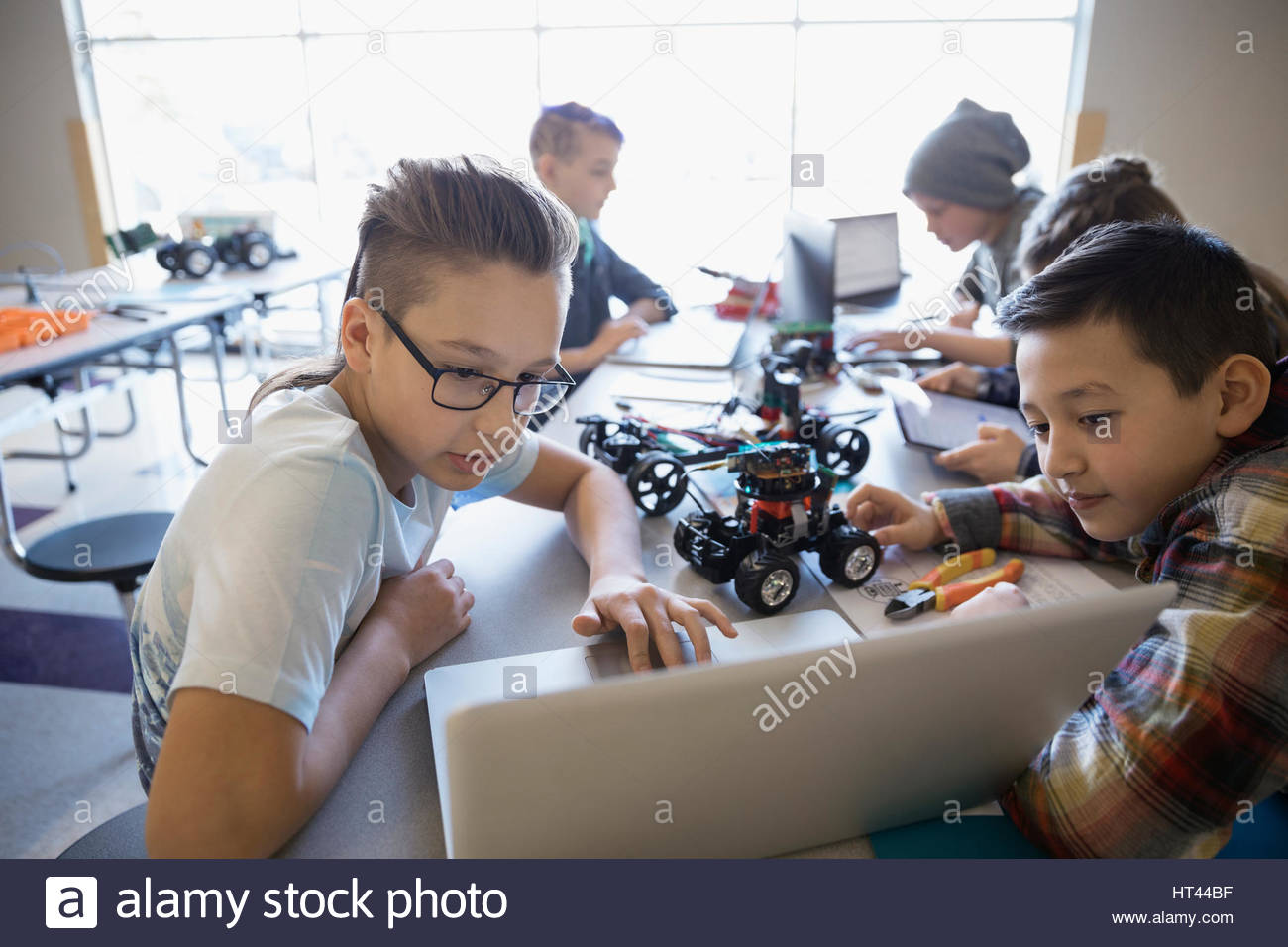 Pre-adolescent boys assembling and programming robotics at laptop in ...