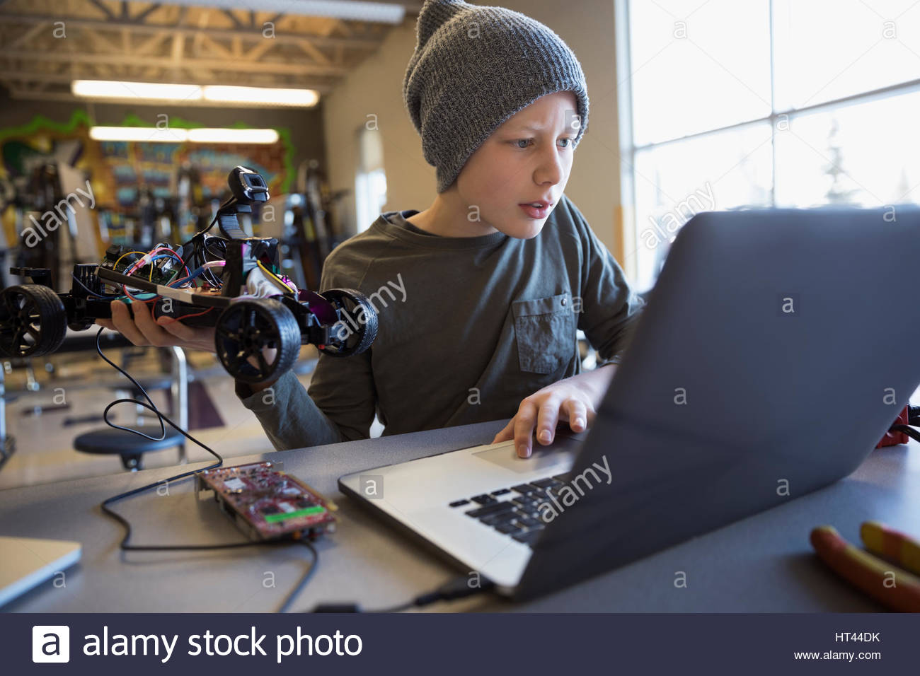 Pre-adolescent boy programming robotics at laptop in classroom Stock ...