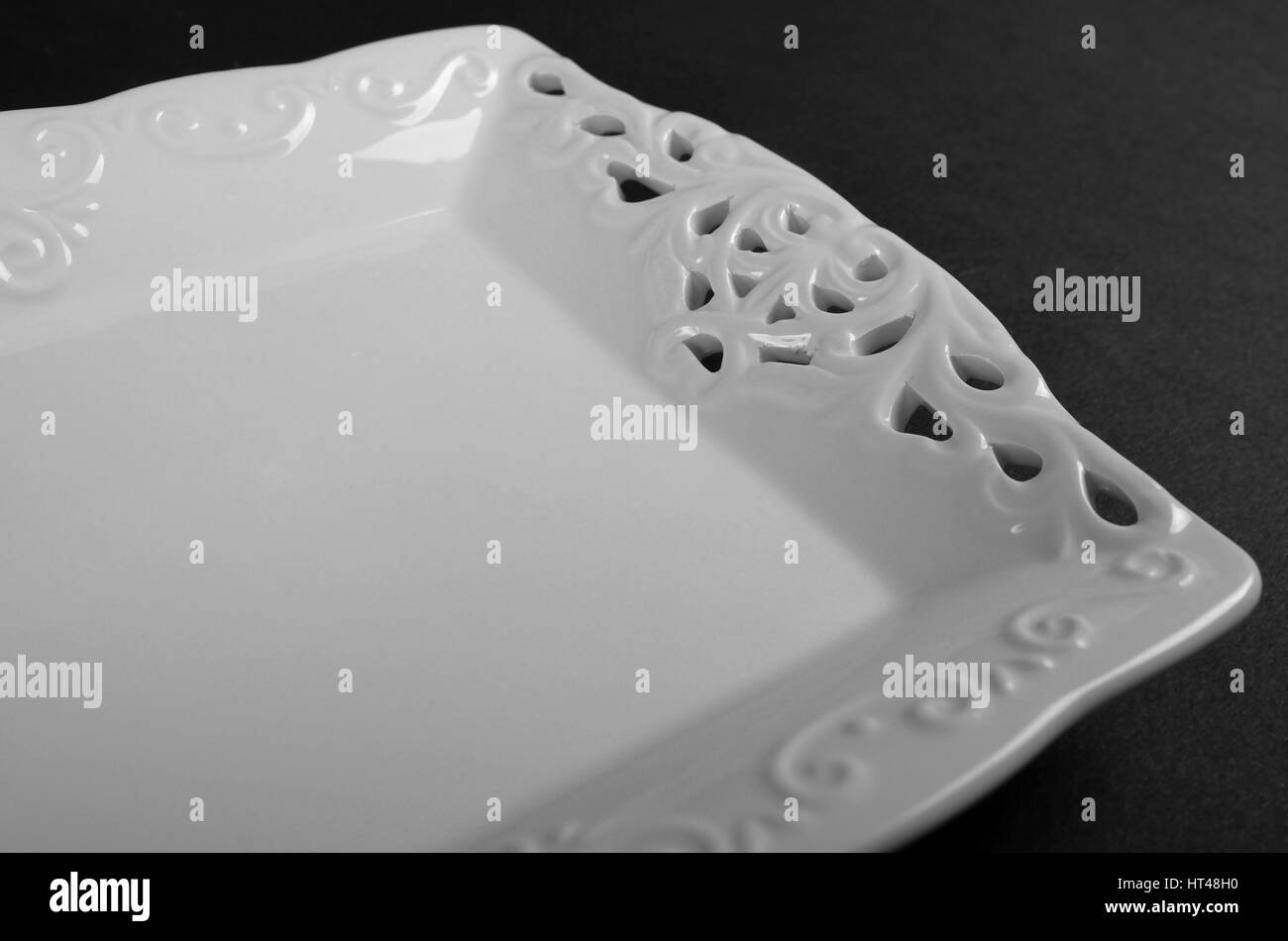 Detail of square shallow bowl serving dish isolated on black background ...