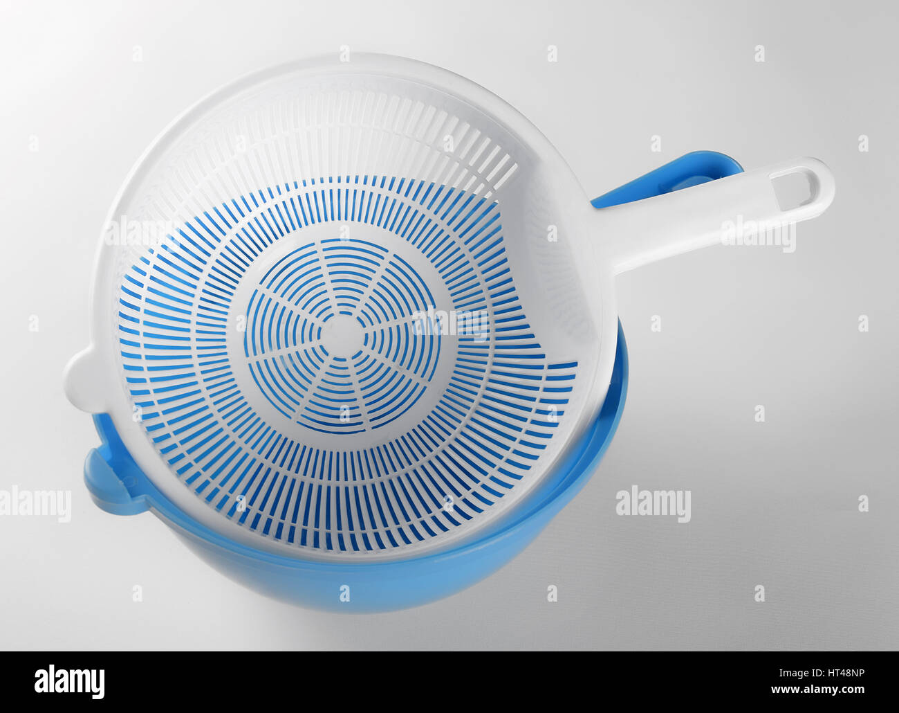White plastic colander in blue bowl isolated on white background Stock ...