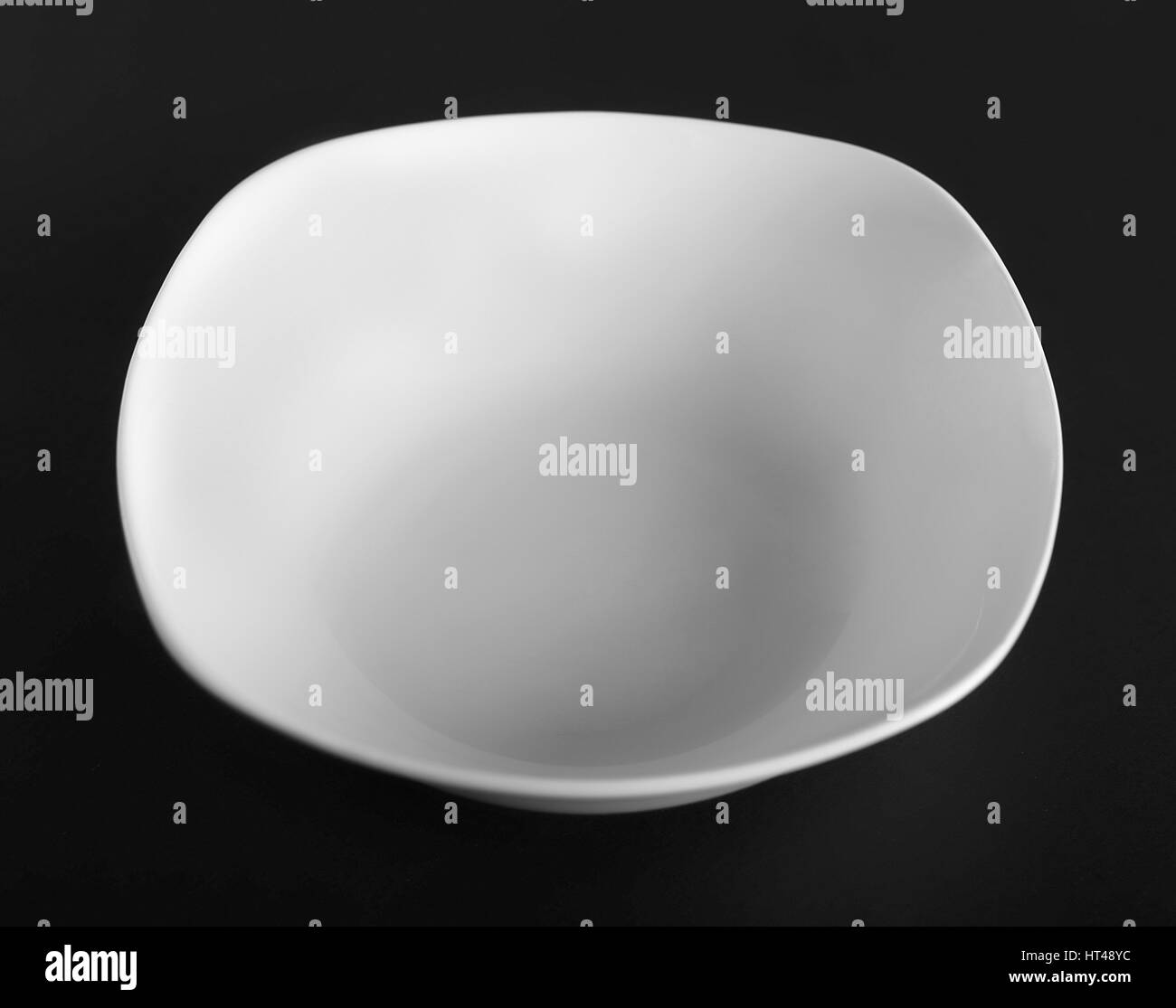 Deep round porcelain dish. White bowl on black background, front view ...