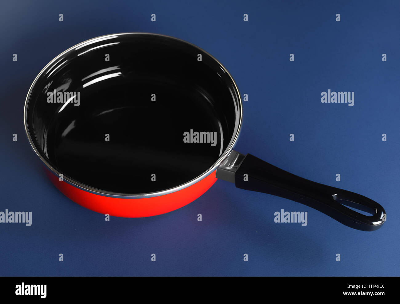 Red enamel pan with handle on blue background, top view Stock Photo - Alamy