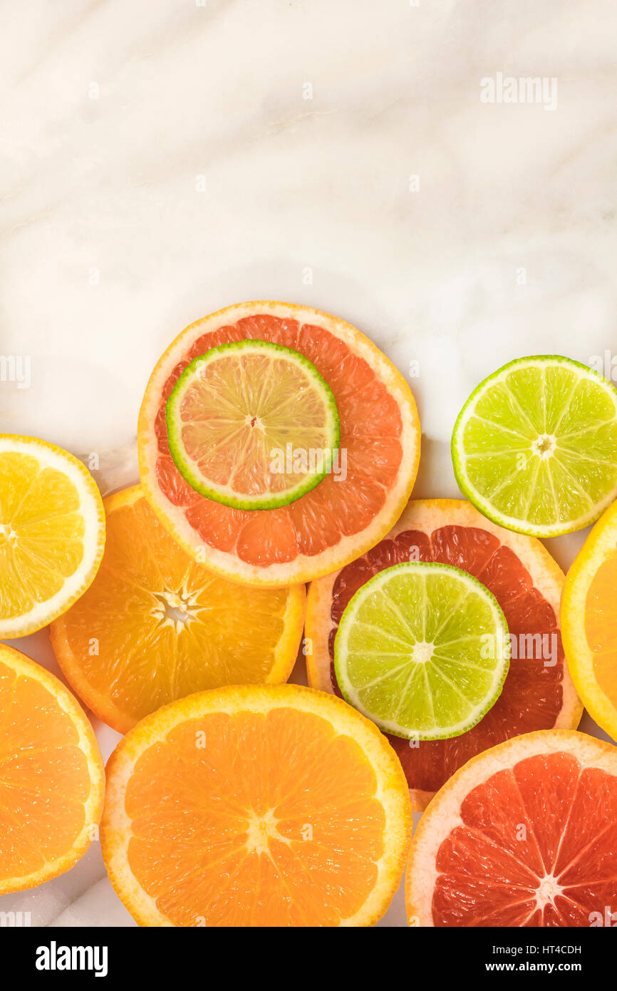 Vibrant juicy citrus fruits on a white marble texture with copy space ...