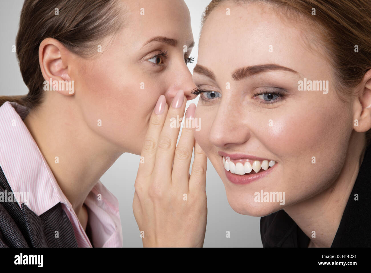 Close Up Shot Of Two Happy Pretty Business Women Sharing A Secret And