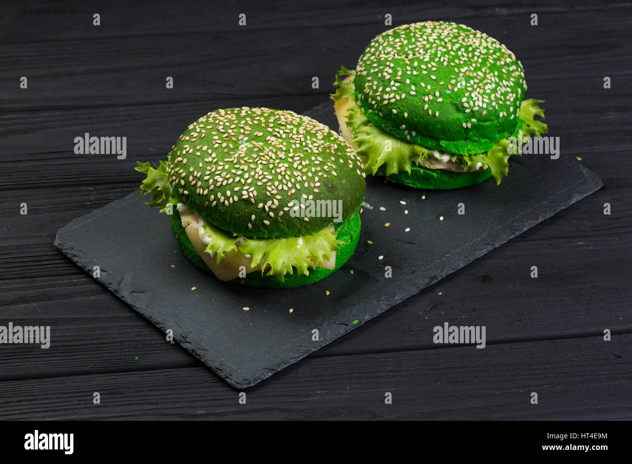 Green burger with lettuce on a black wooden background Stock Photo - Alamy