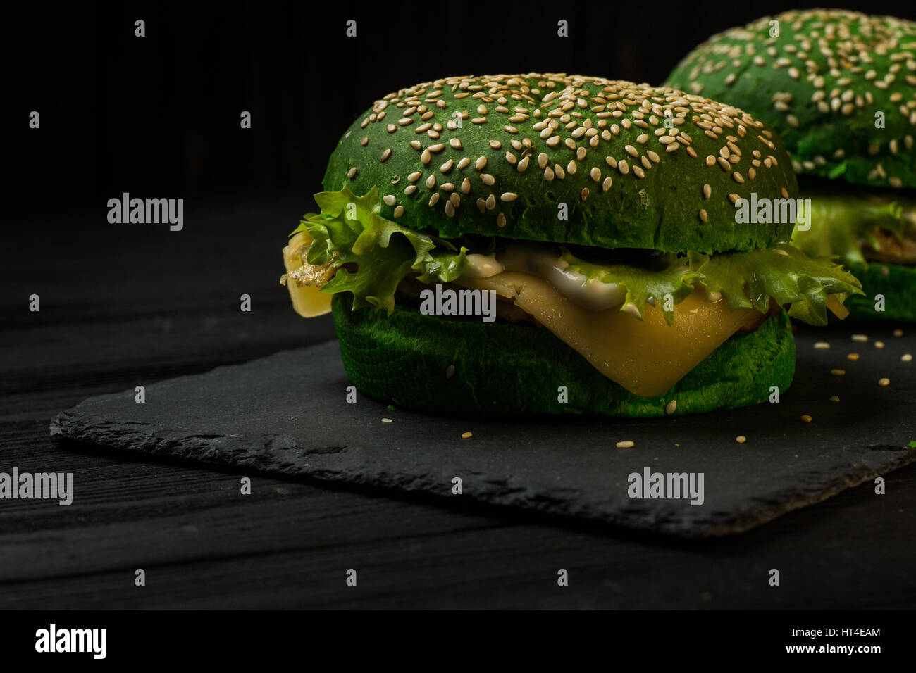 Green burger with lettuce on a black wooden background Stock Photo - Alamy
