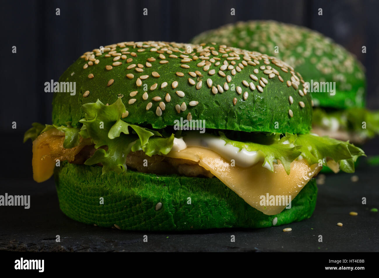 Green burger with lettuce on a black wooden background Stock Photo - Alamy