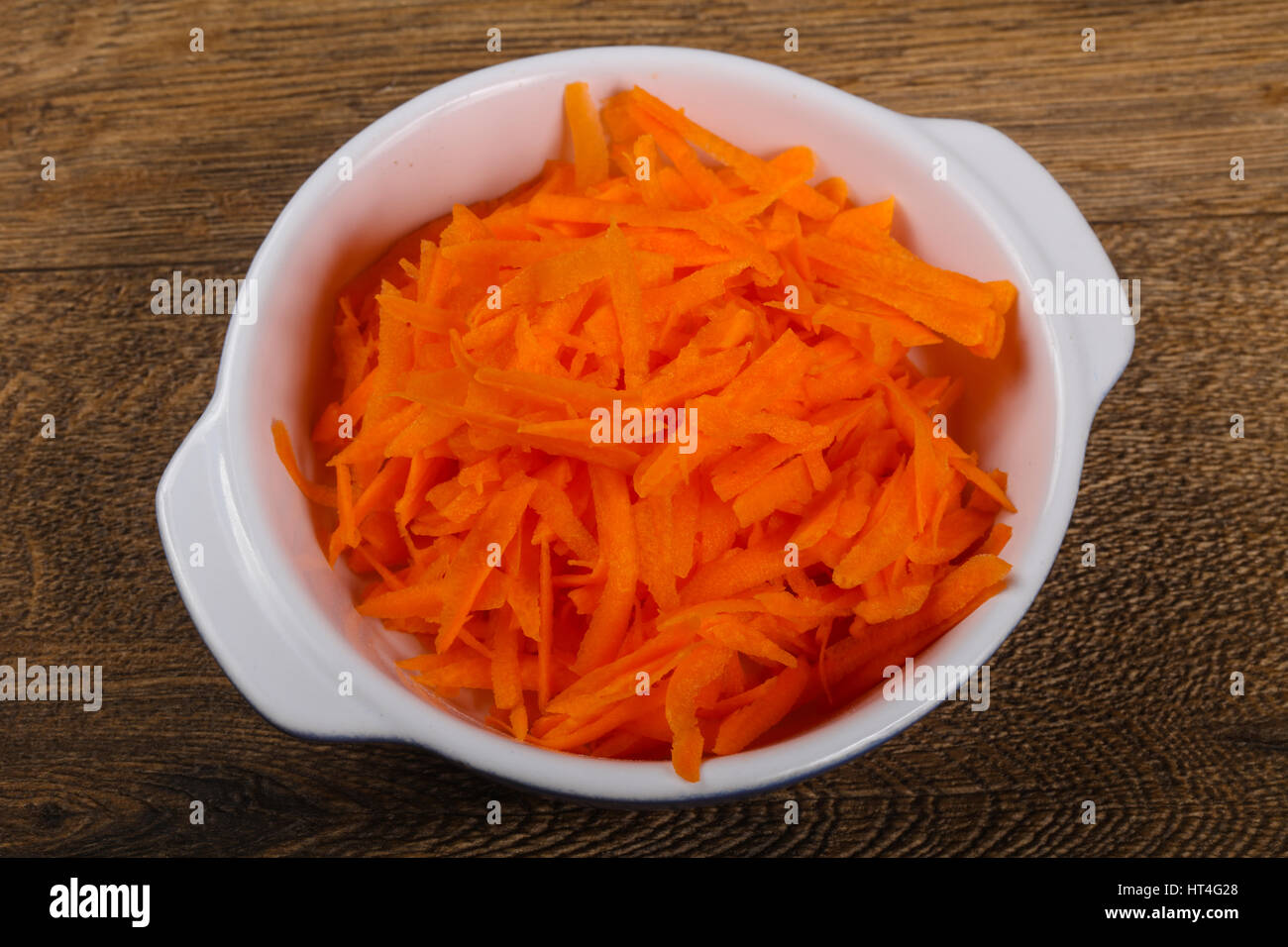 Shredded carrot heap in the bowl over wooden background Stock Photo - Alamy