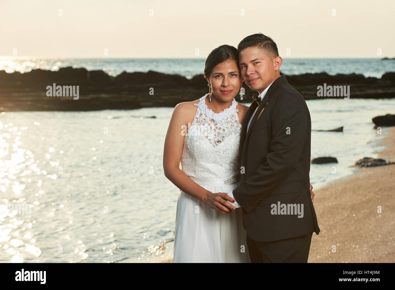 Portrait of young hispanic married couple on sunset ocean beach. Happy ...