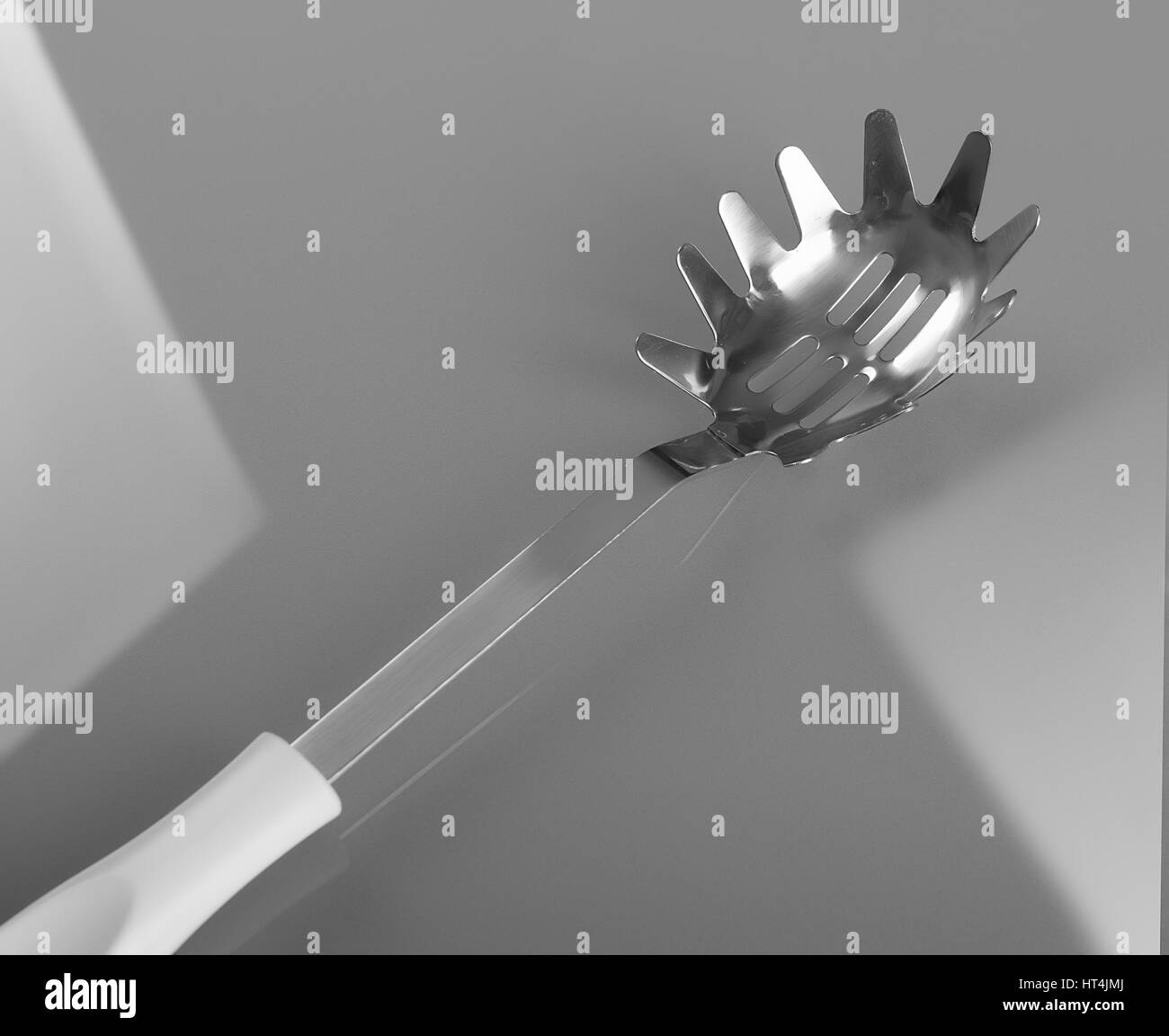 Spaghetti draining utensil on gray background Stock Photo - Alamy