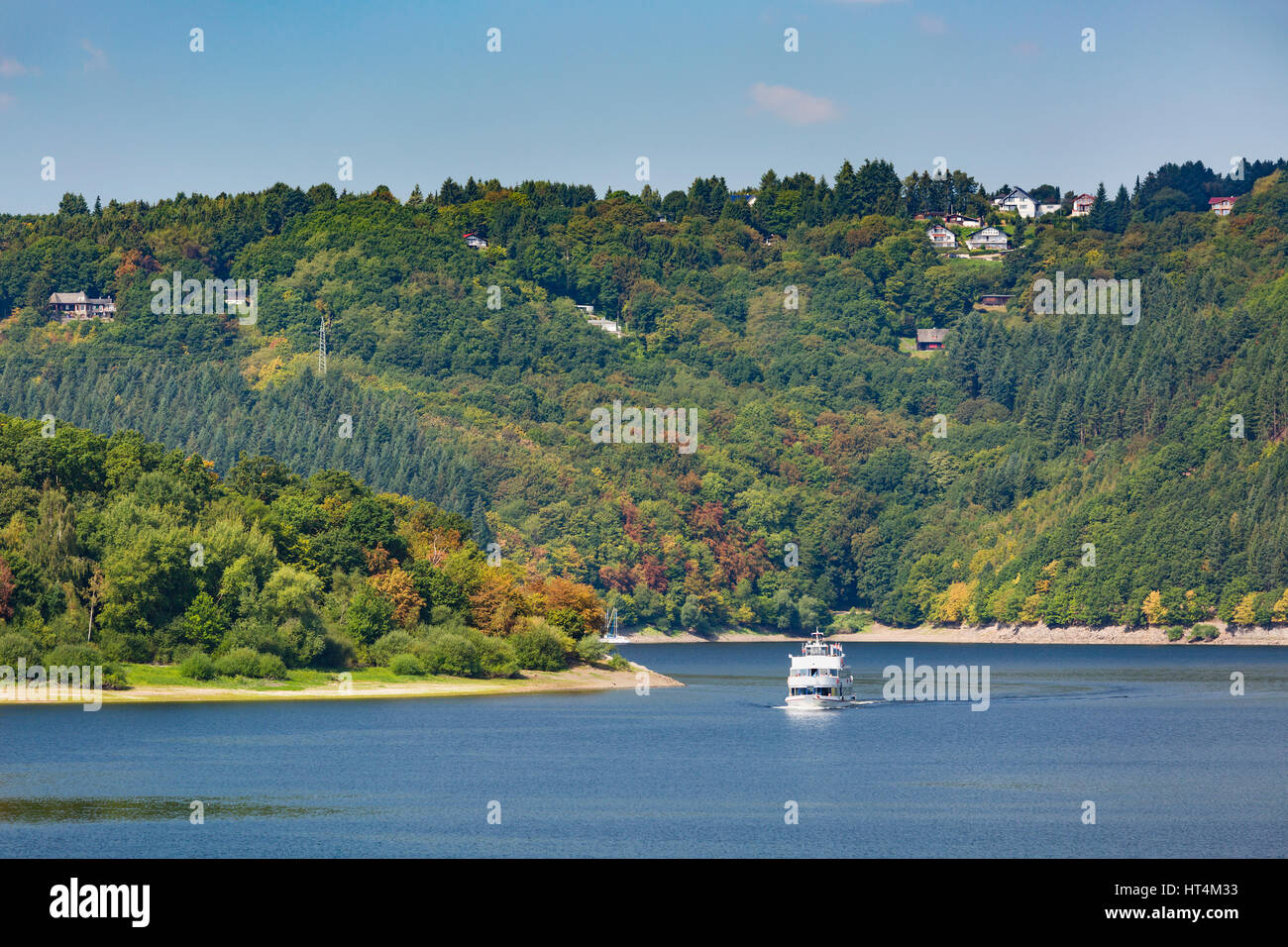A tourist boat on Lake Rursee in summer with some houses in the hills ...