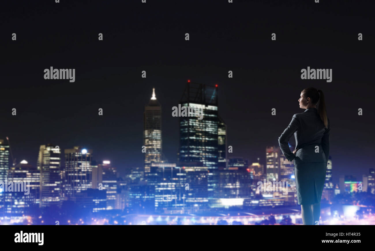 Rear view of elegant businesswoman viewing lights of night city Stock ...