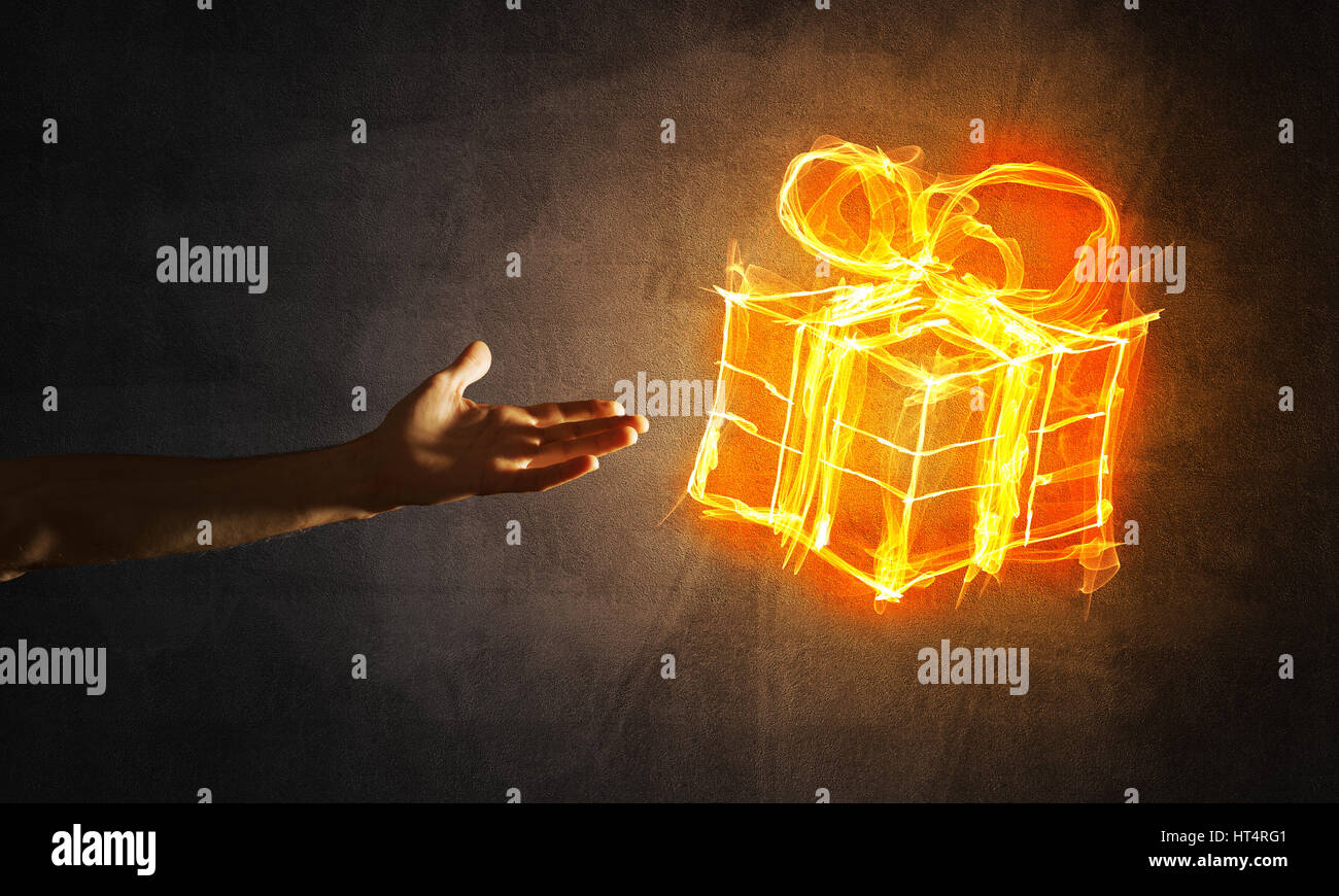 Glowing fire gift box icon in palm on dark background Stock Photo - Alamy